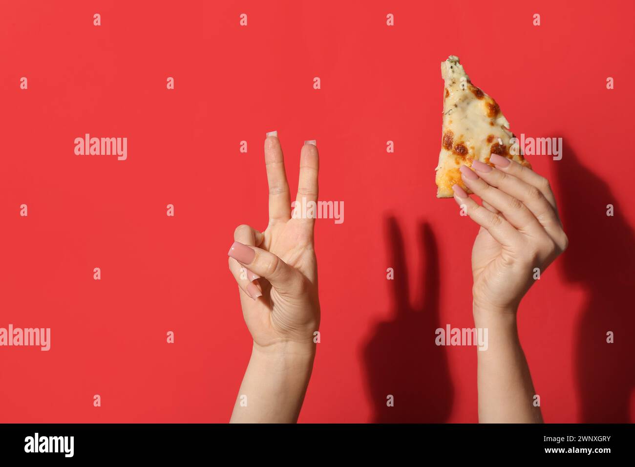 Female hand holding tasty pizza slice and making piece symbol on red ...
