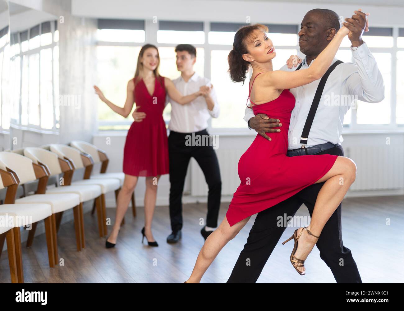 Woman in red and African American performing tango in dance class Stock ...