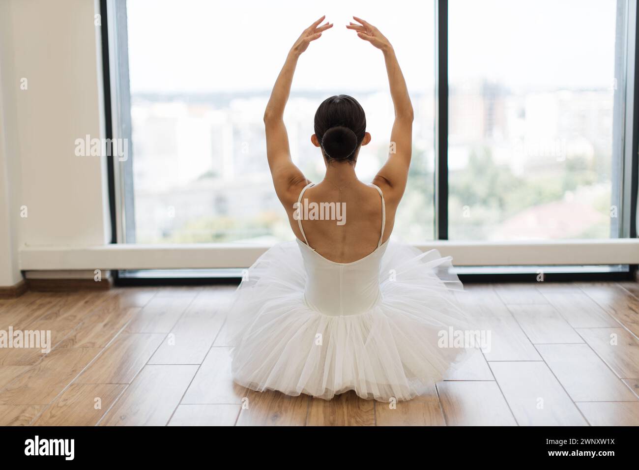 Focused young ballerina dressed in white tutu costume practice ballet ...