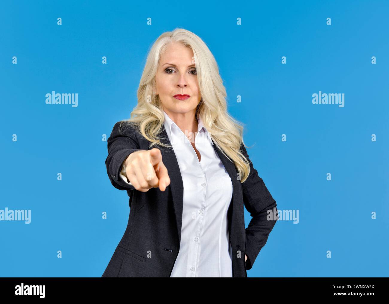 Attractive business woman against blue background pointing with stern ...