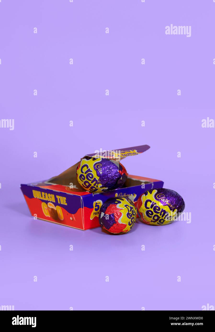 Opened box of opened Cadbury Creme Eggs against a light purple ...