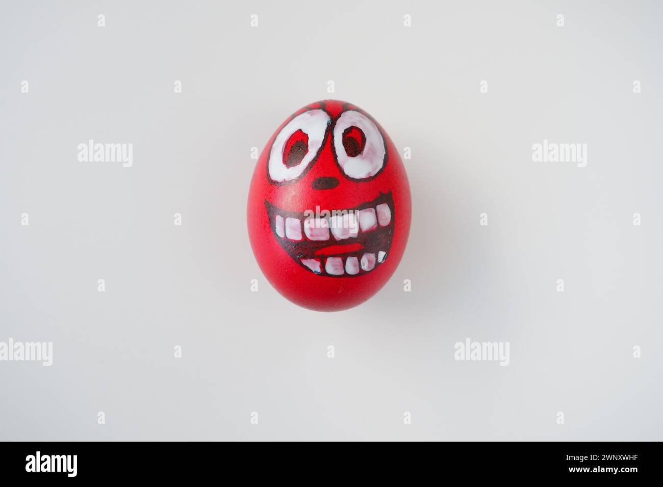 Easter egg painted red, white and black with a cheerful toothy face ...