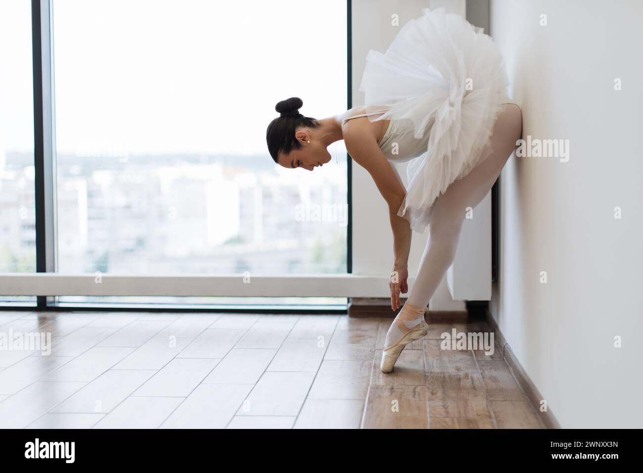 Beautiful graceful ballerina in white practice ballet plie positions ...