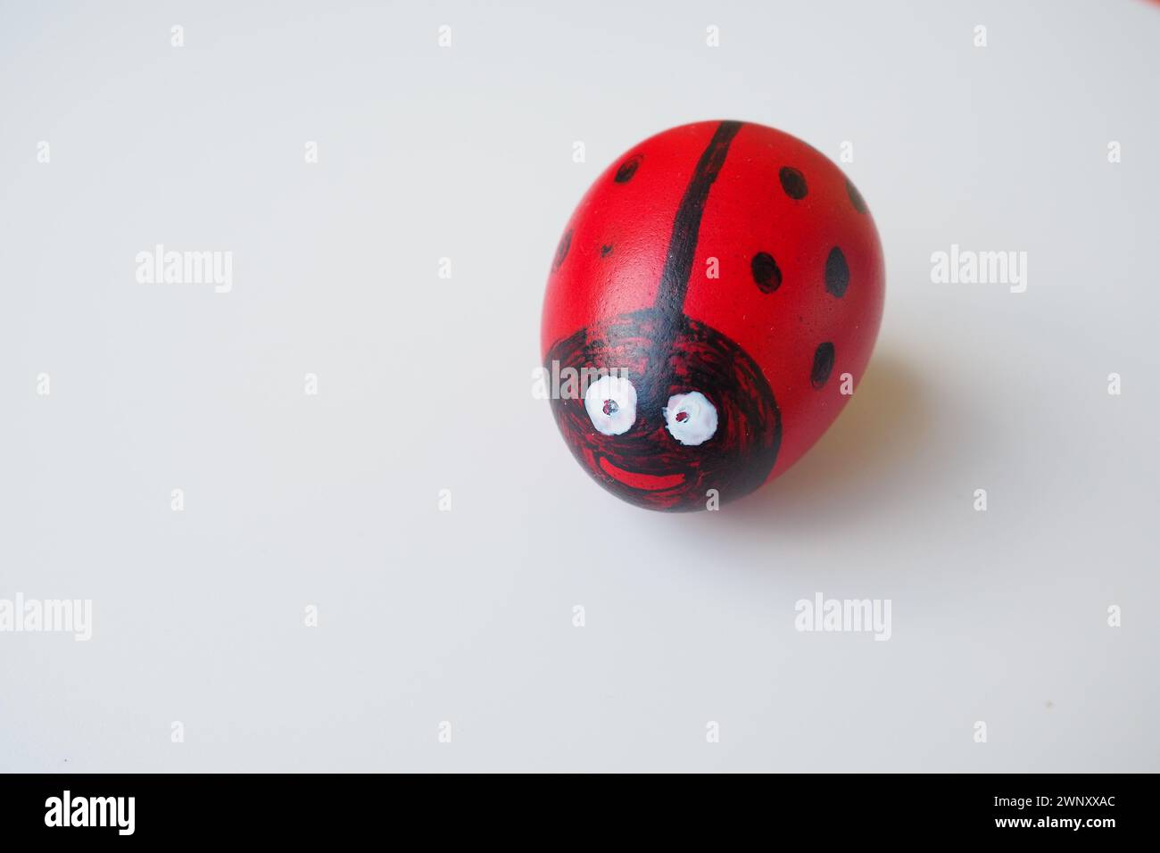 Easter egg painted red, white and black with a cheerful face of ladybug ...