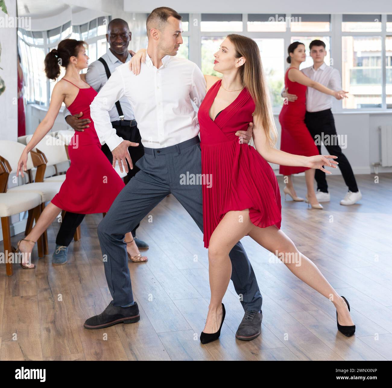 Happy young man and woman in elegant clothes performing ballroom dance ...