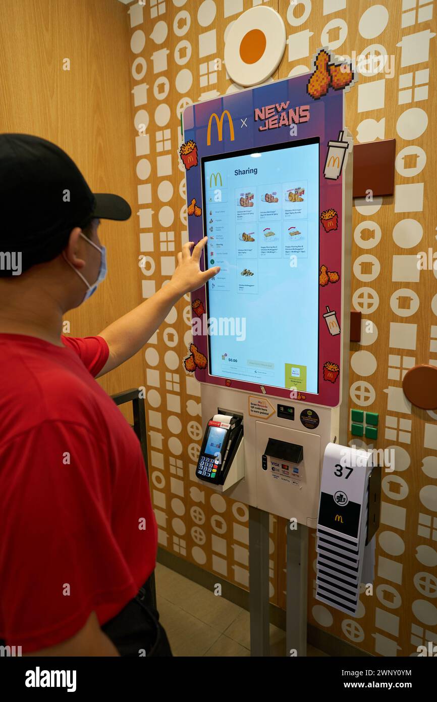 SINGAPORE - NOVEMBER 06, 2023: a man use self-service kiosk inside ...
