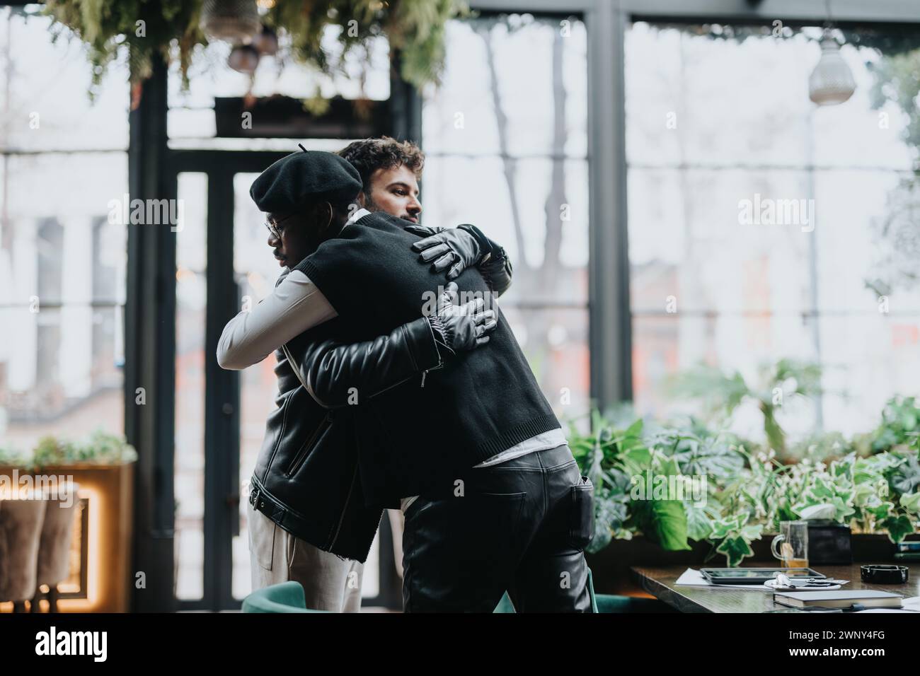 Two people sharing a heartfelt hug in a bright, plant-filled cafe ...