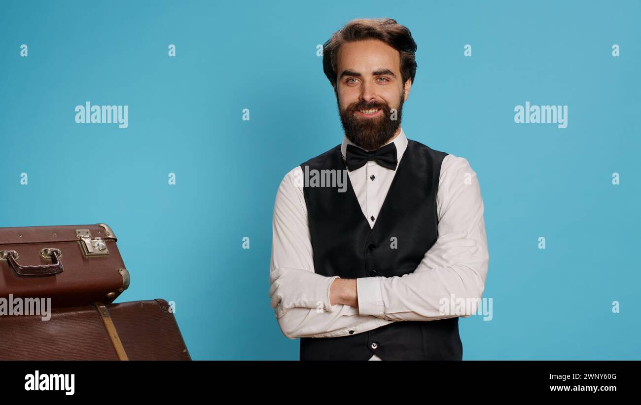 Professional hotel concierge posing on camera against blue background ...