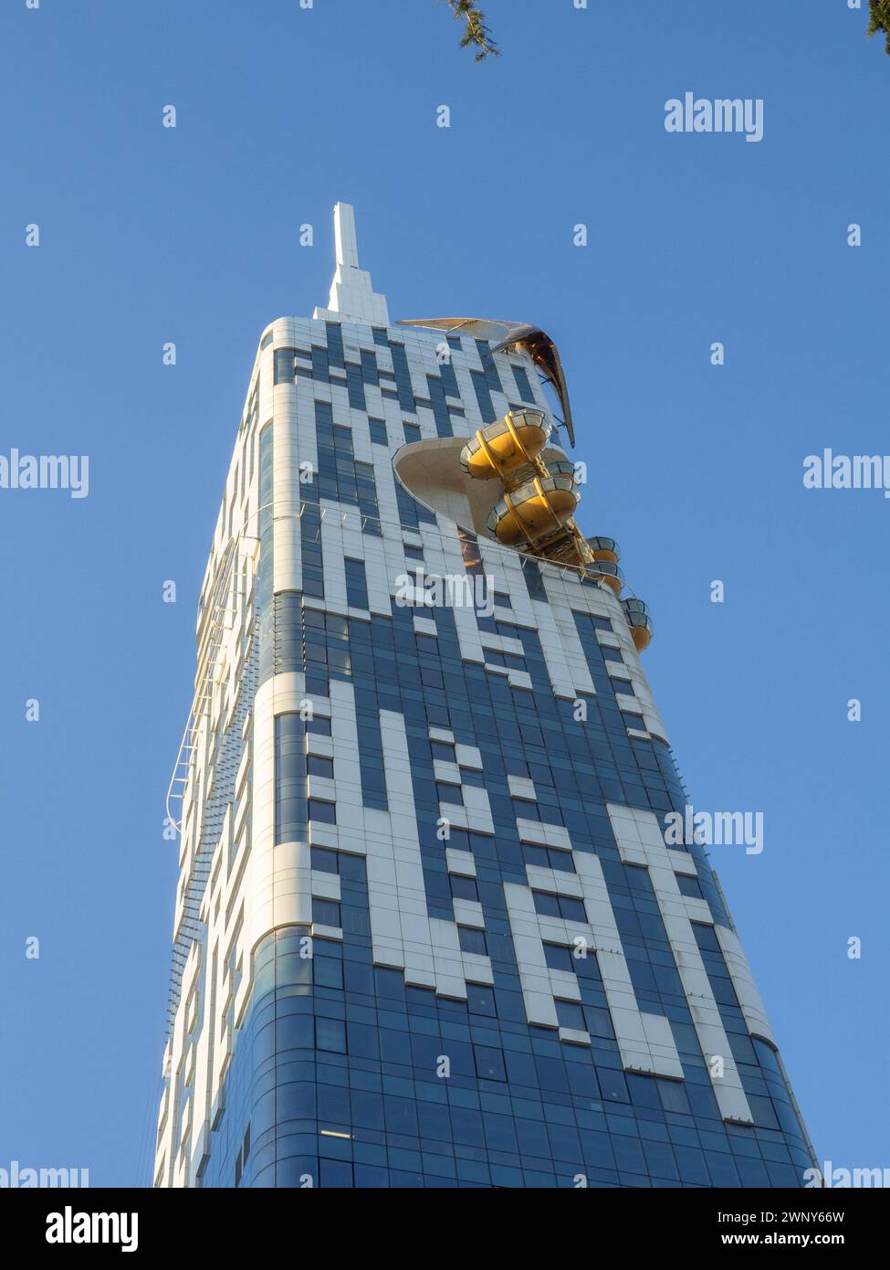 A tall building with a spire and a carousel. Architecture of Batumi ...