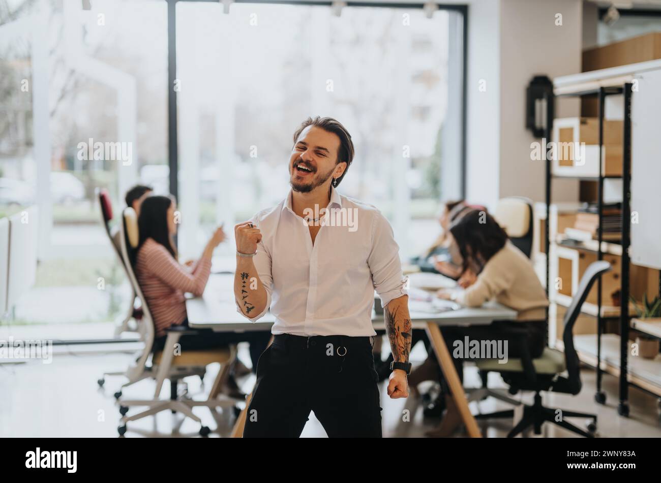 Energetic male entrepreneur with tattoos showing success gesture ...