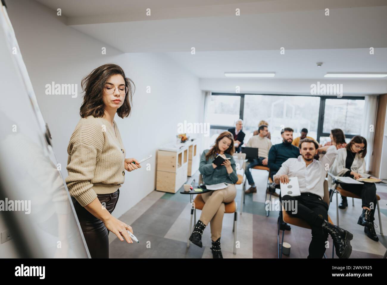 Female coach with a marker in hand engagingly explaining business ...