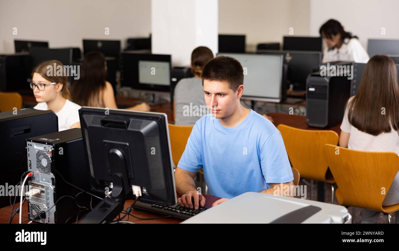 Smart male teen learning computer science while she is using a PC in ...