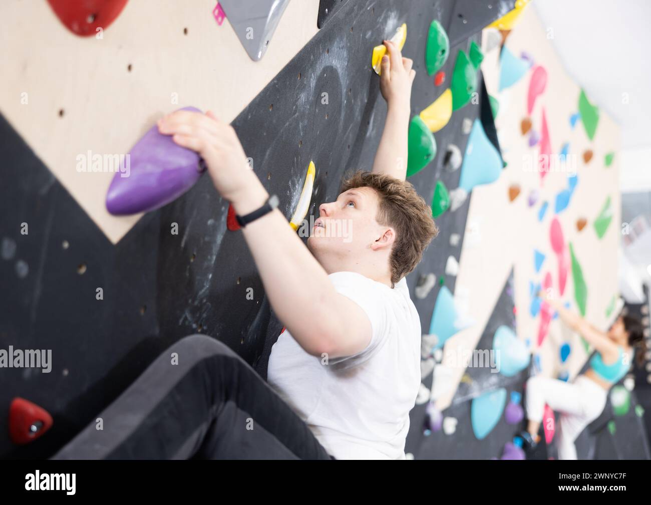 Teenage boy climbs steep artificial wall in sports complex and trains ...