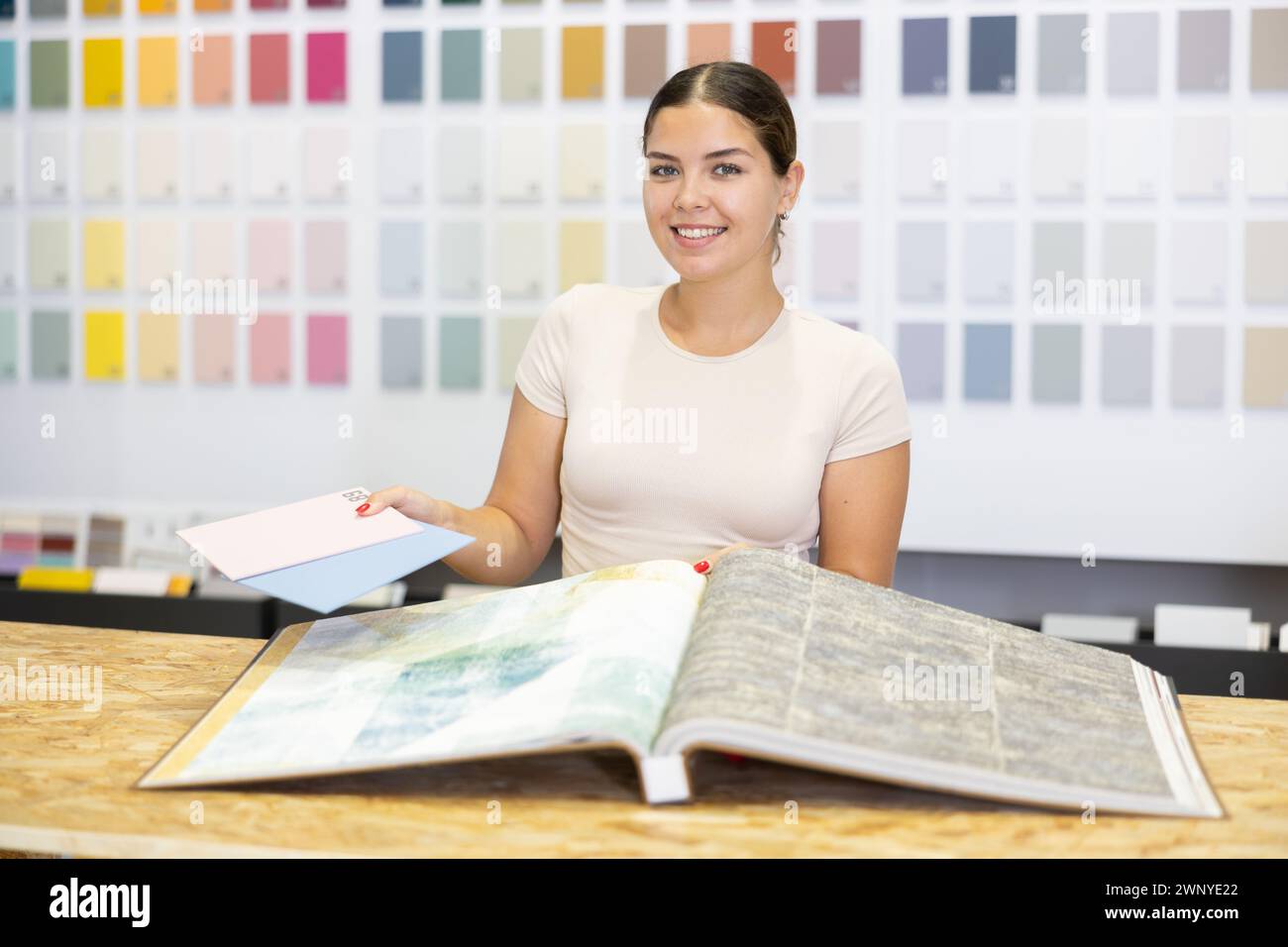 Positive young woman picking paint colors from catalog in store Stock ...
