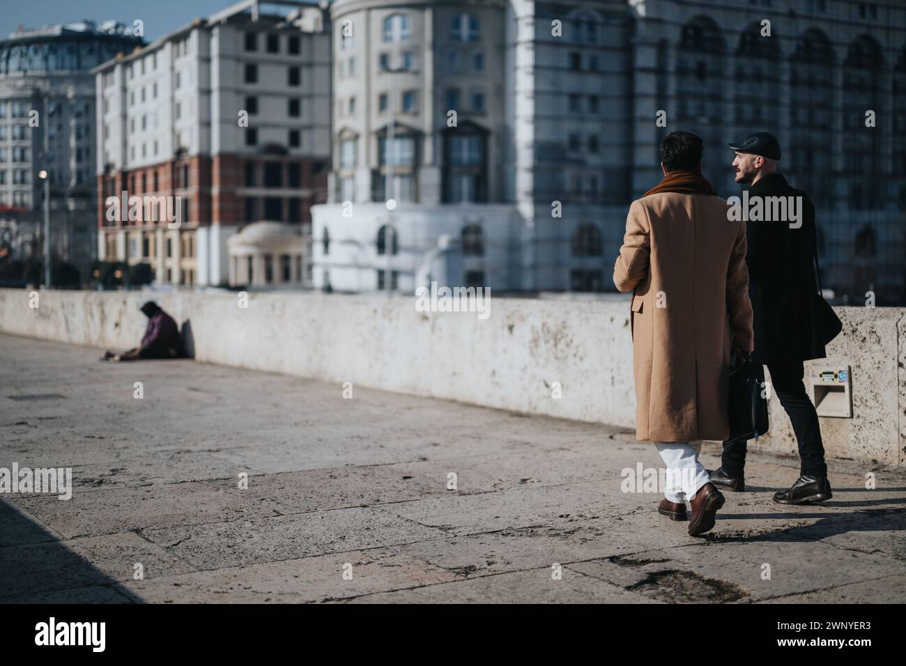 Two men engaging in a casual conversation on an urban bridge with ...