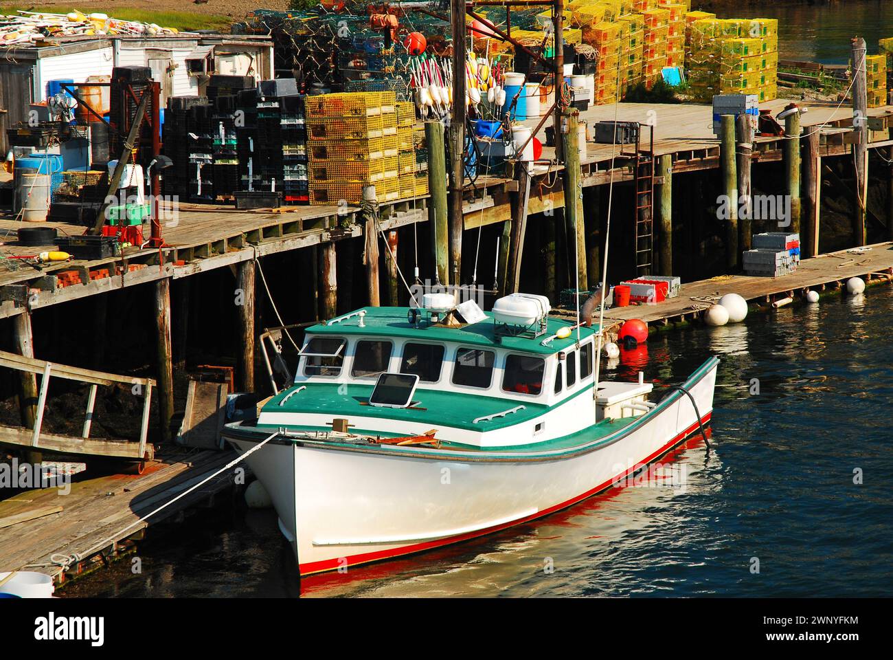 A commercial lobster boat is docked at low tide surrounded by lobster ...