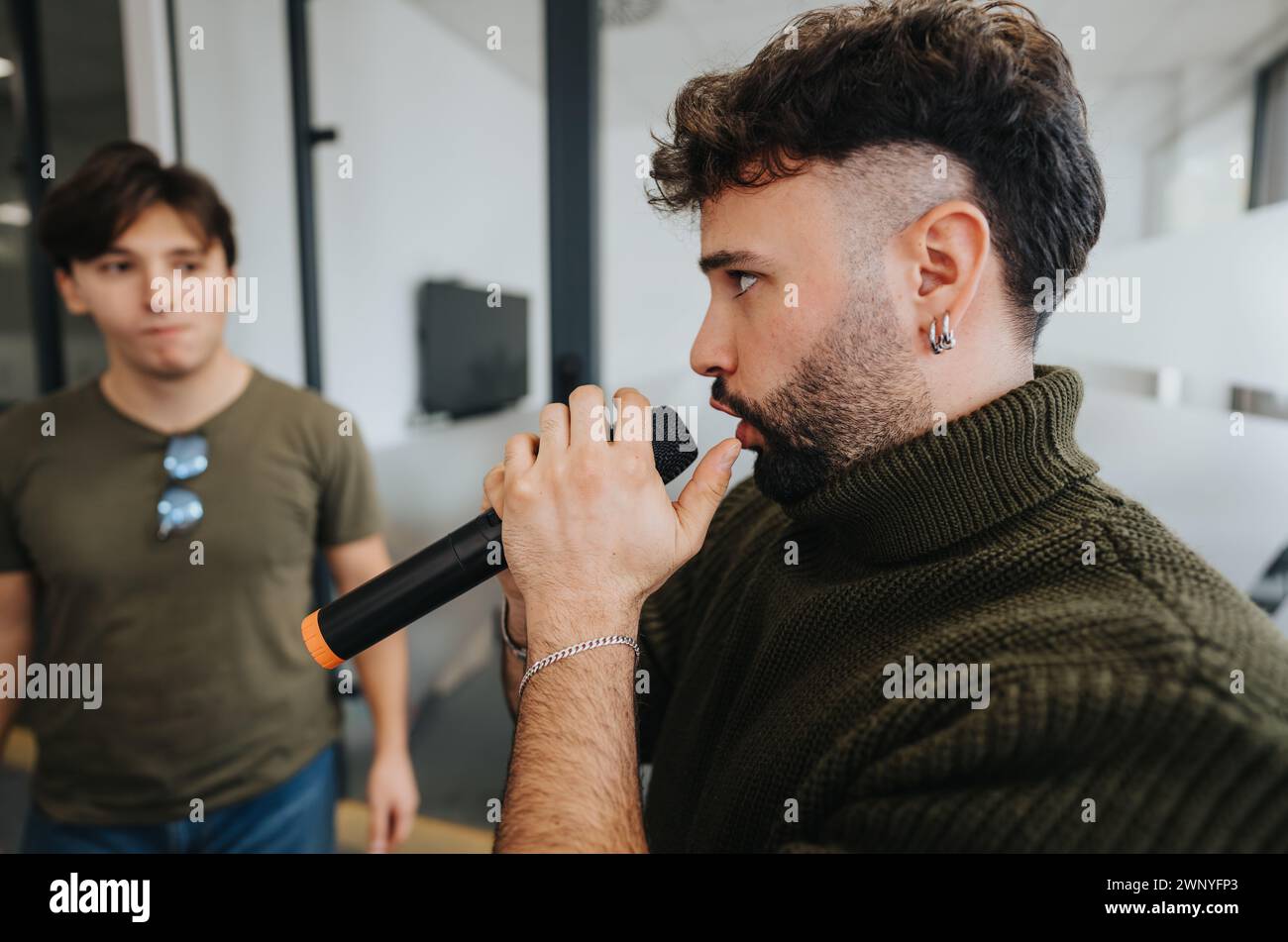 Handsome man singing for his teammates at work while taking a break ...