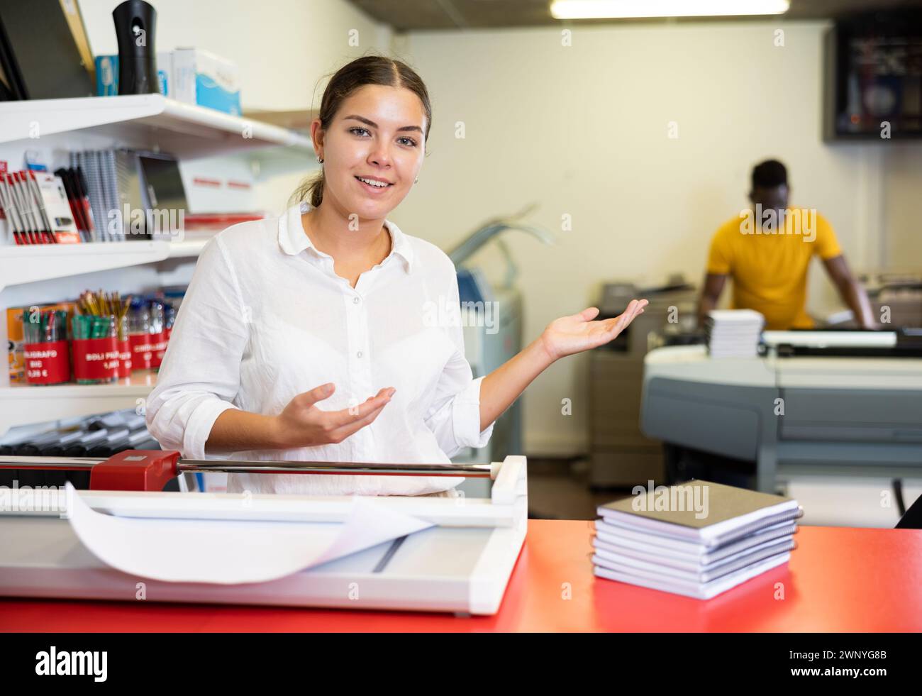 Portrait of happy young female typographer using paper cutter cutter ...