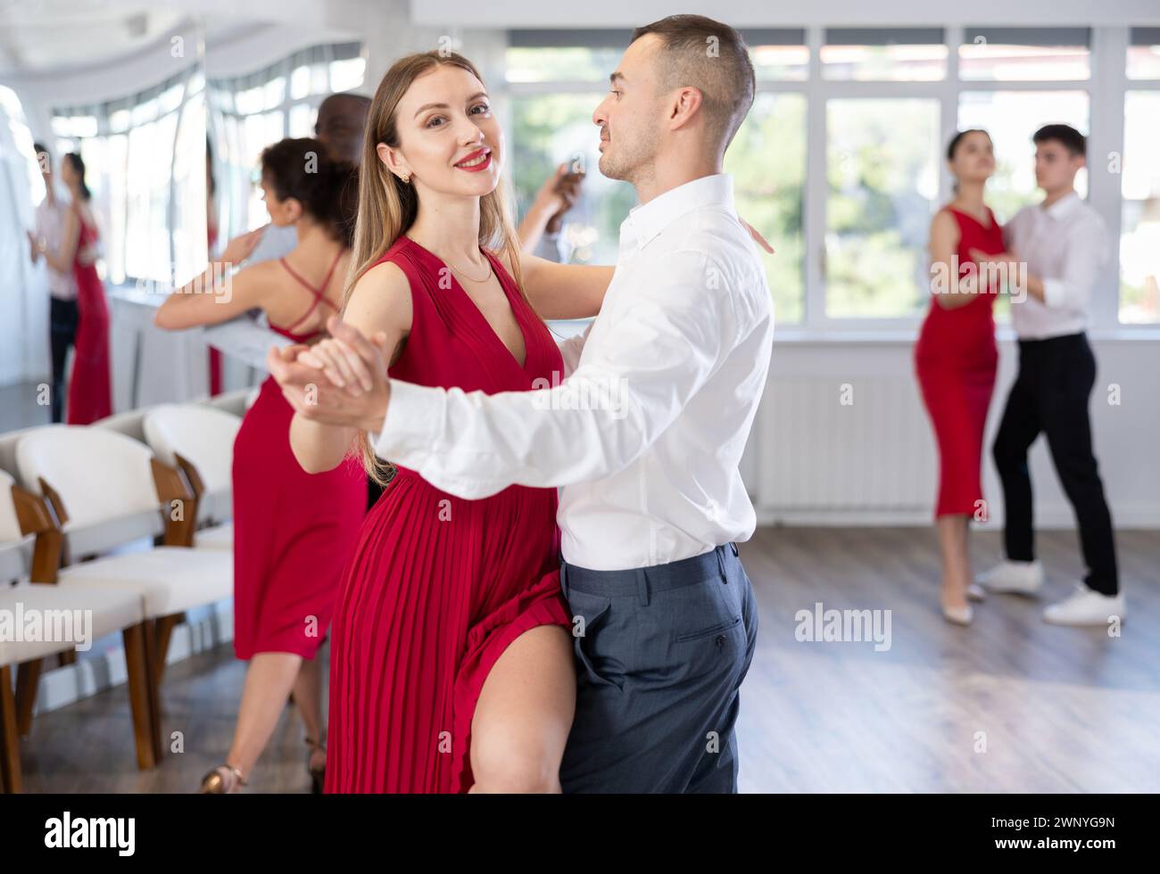 Happy smiling woman dressed in red dress enjoying waltz with male ...