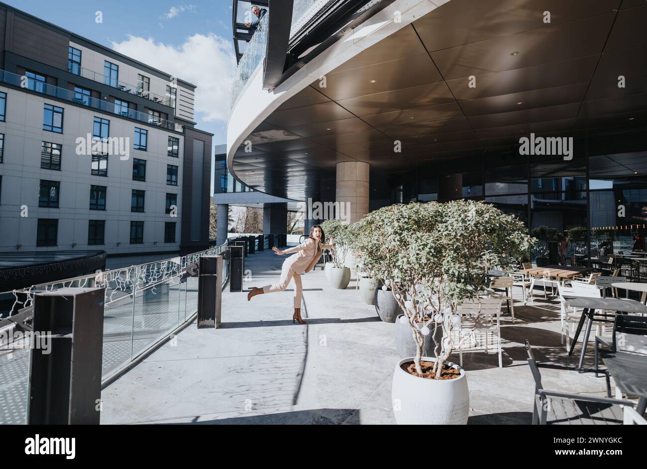 Stylish young woman in a jumpsuit playfully balances on one leg ...