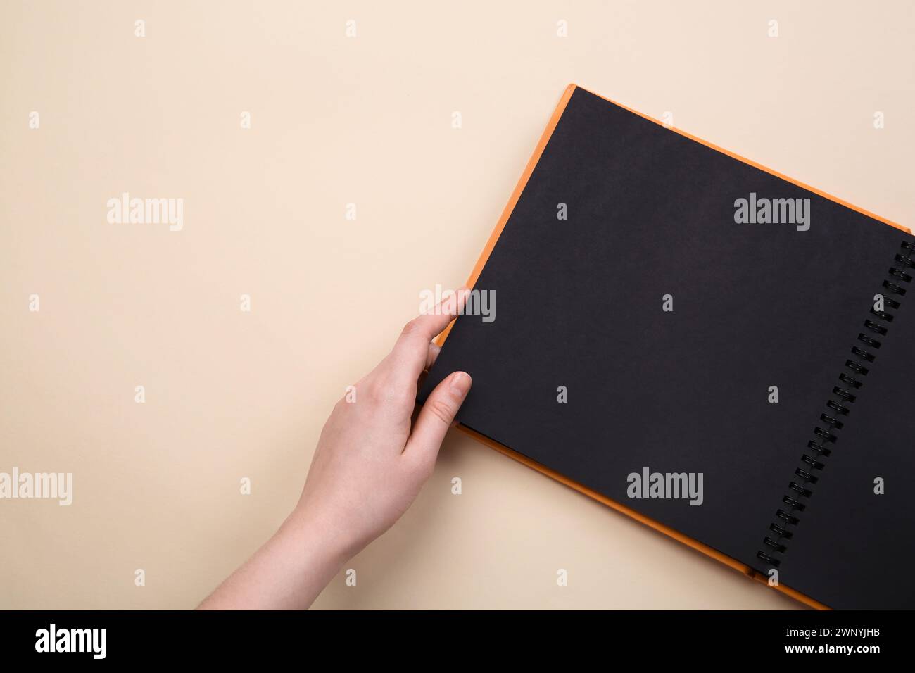 Woman with open photo album at beige background, top view. Space for ...