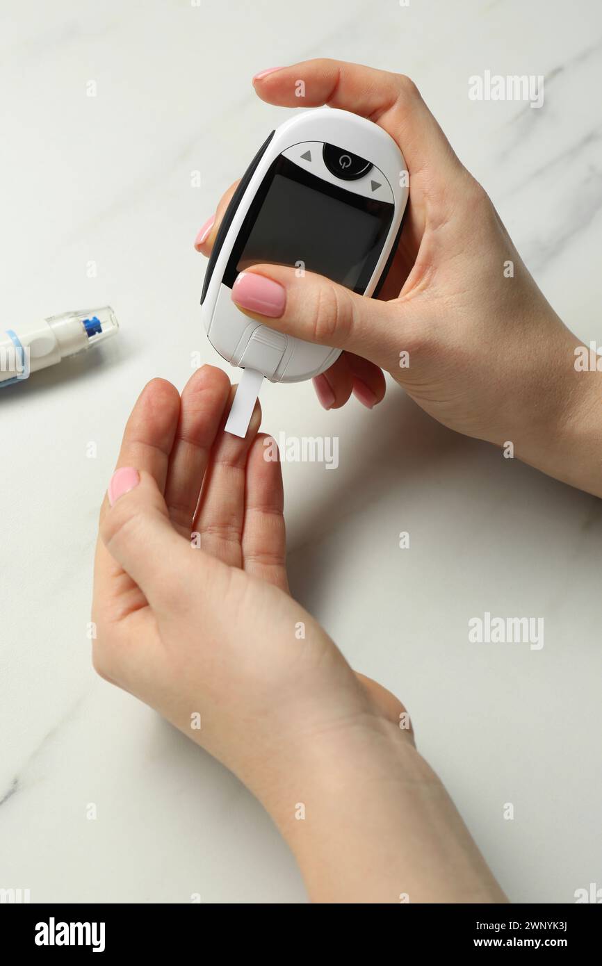 Diabetes. Woman checking blood sugar level with glucometer at white ...