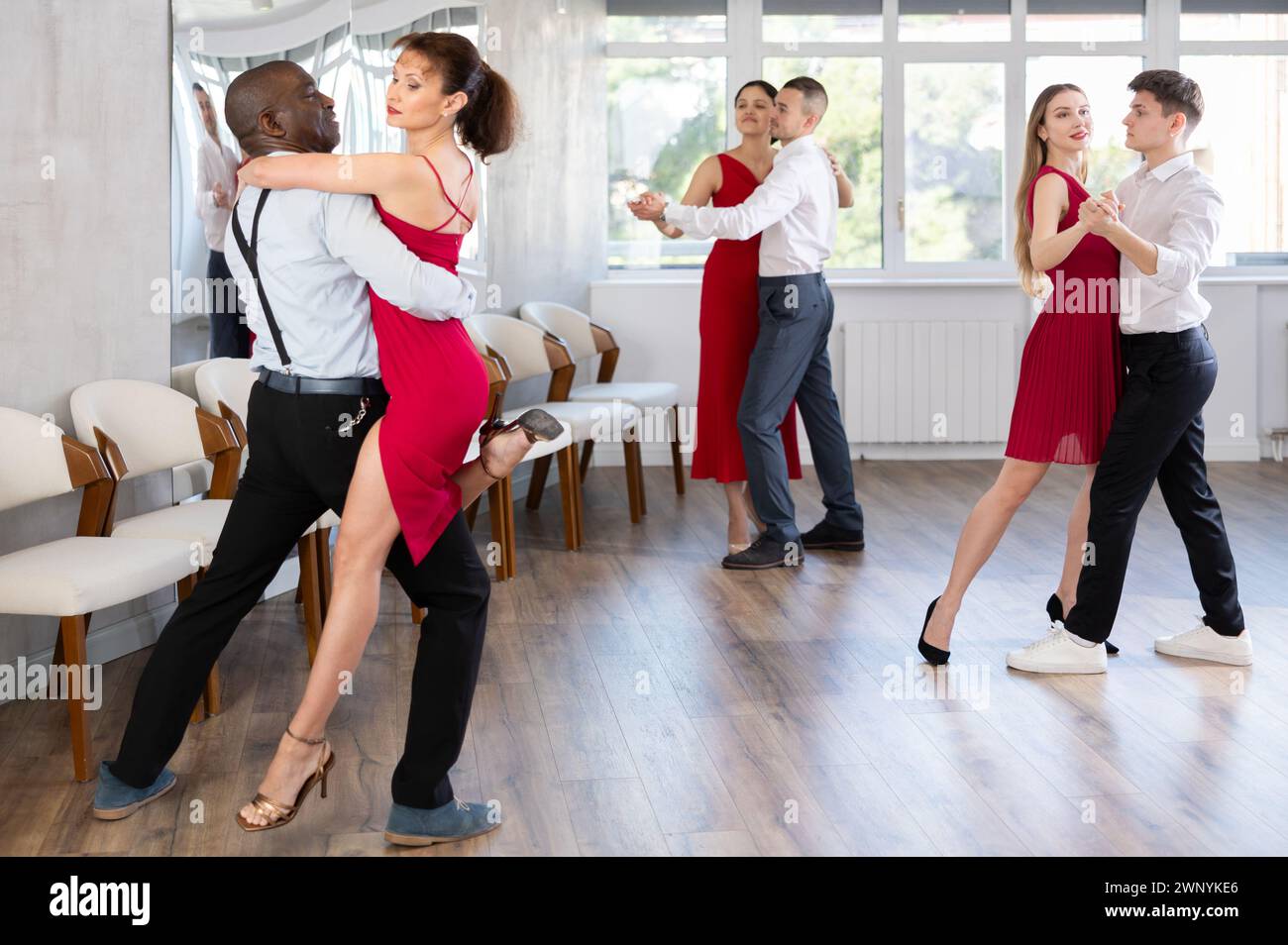 Positive dancing multinational couple enjoying active samba dance in ...