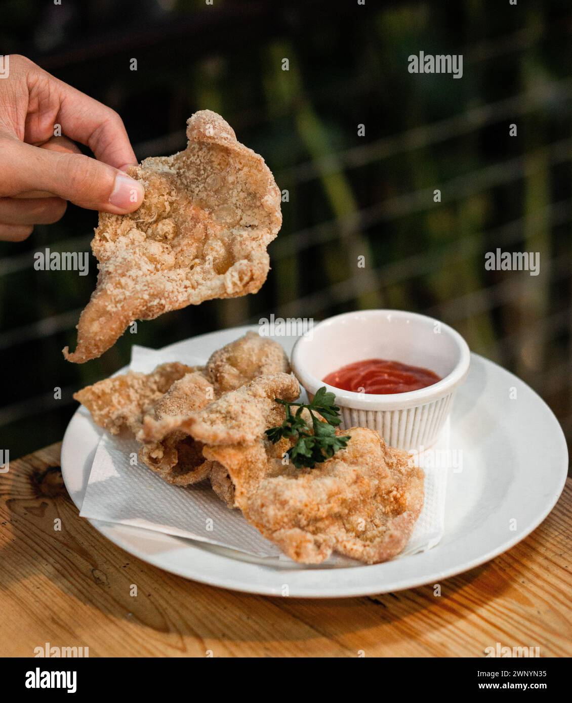 a close up photo of crispy fried chicken skin served with chilli sauce ...