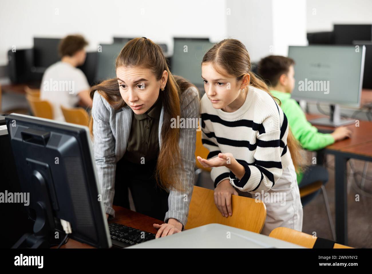 Female teacher and teenage girl looking at monitor of PC Stock Photo ...