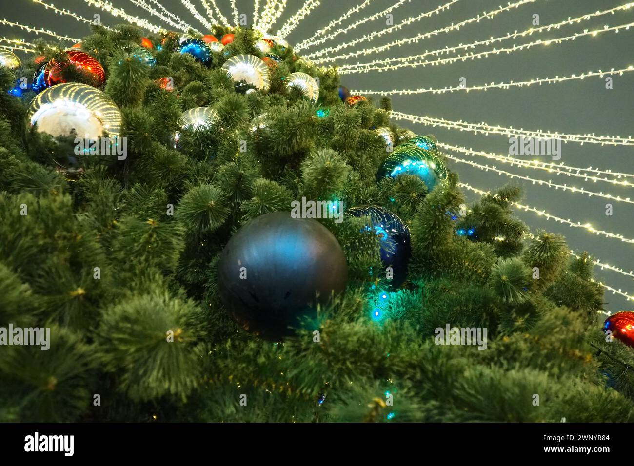 Multi-colored glass shiny balls on the New Year's city tree. Glowing ...