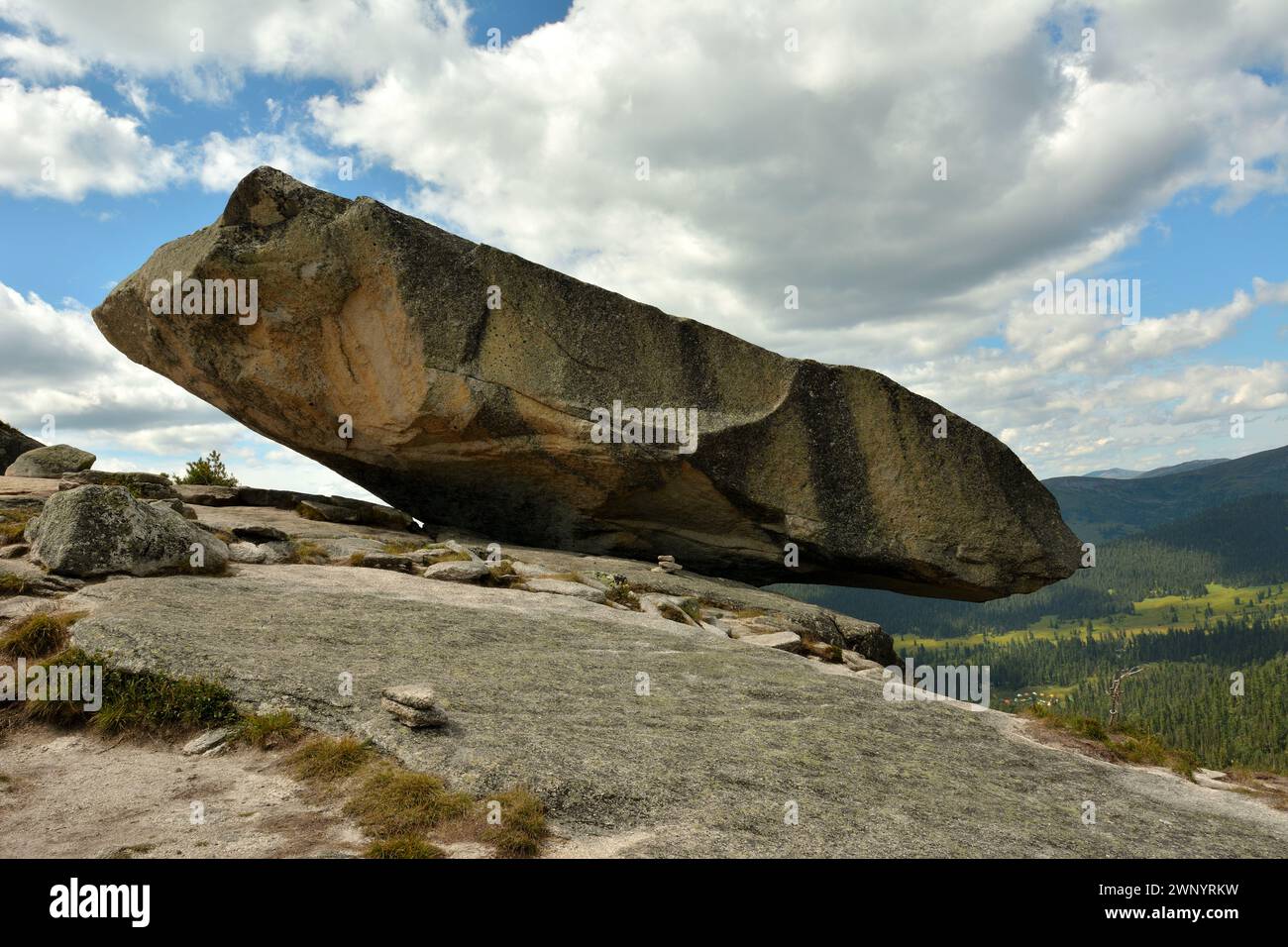A huge stone monolith on the edge of a high mountain hangs over a ...