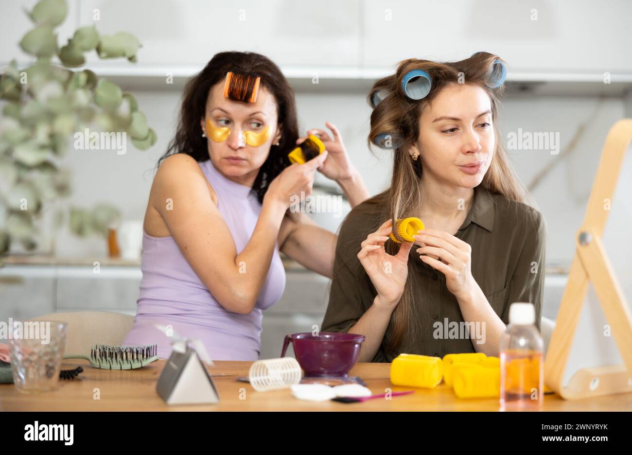 Female friends curling hair with rollers by tabletop mirror Stock Photo ...