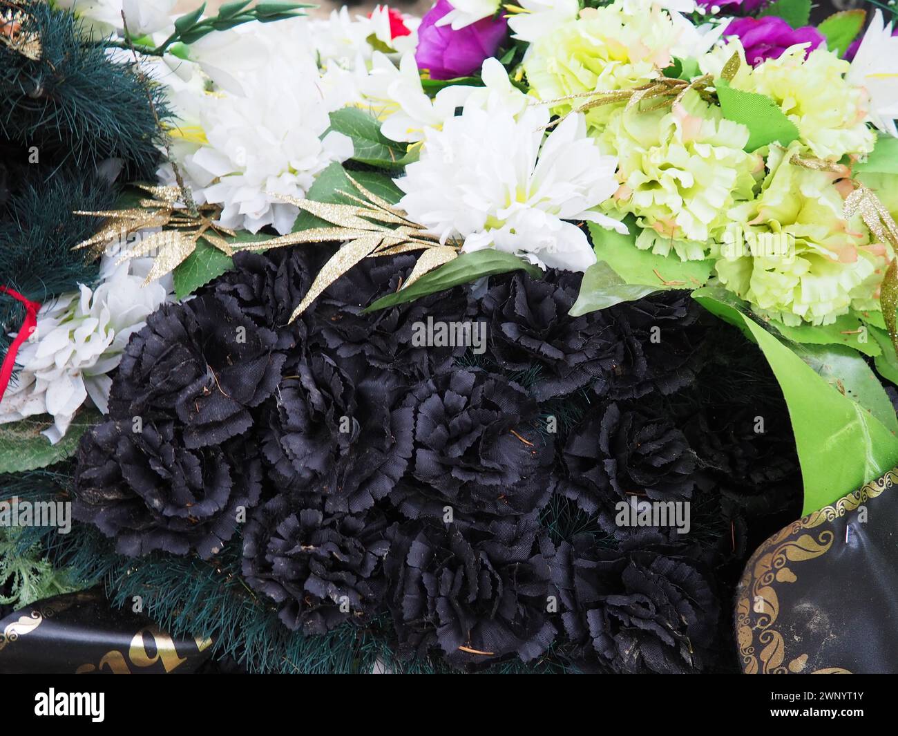 Artificial multi-colored flowers on the grave. Overgrown with grass old ...