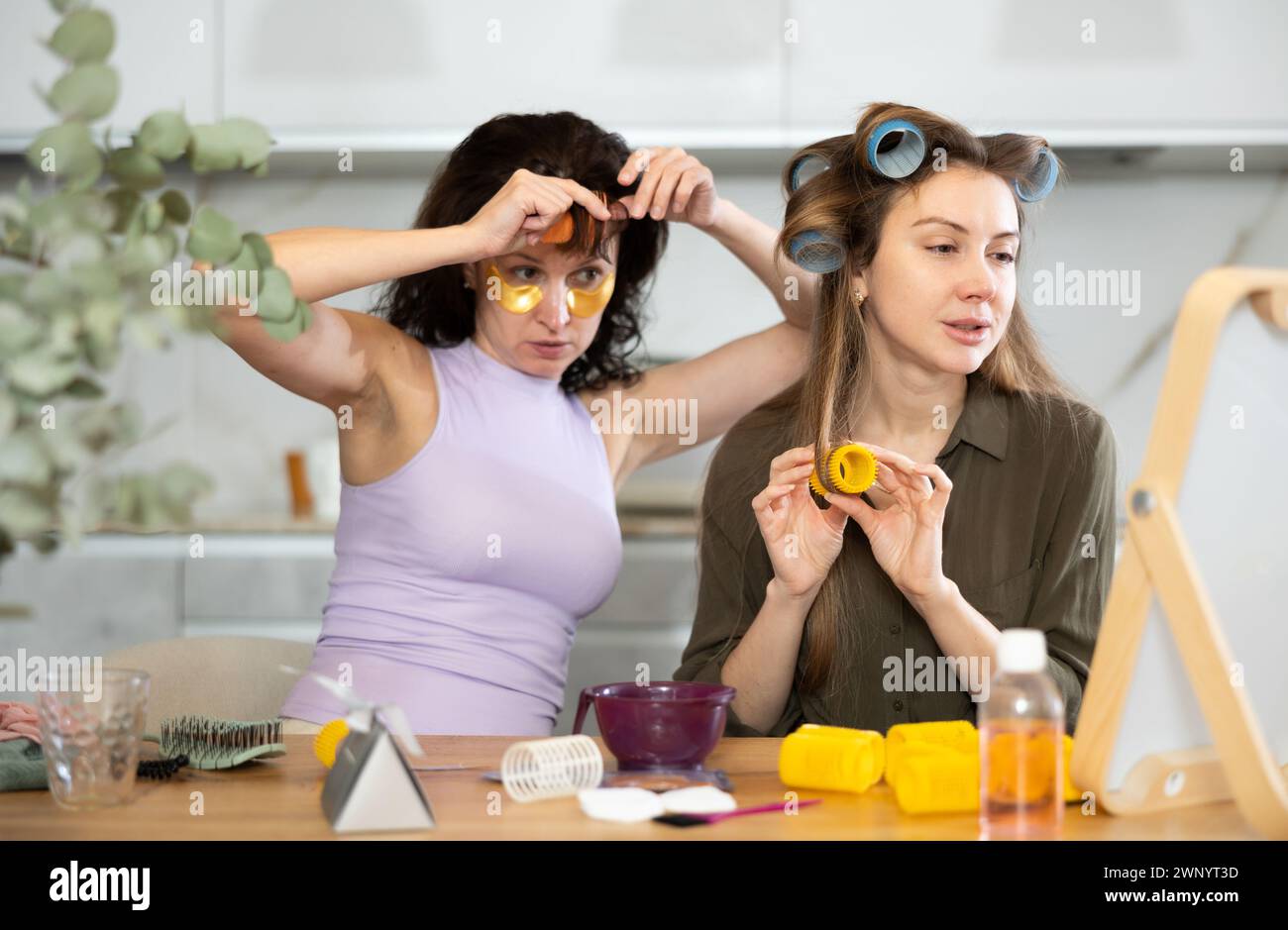 Female friends curling hair with rollers by tabletop mirror Stock Photo ...
