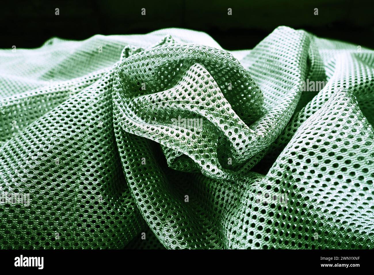 Synthetic fabric with holes, laid in waves and twisted into folds ...