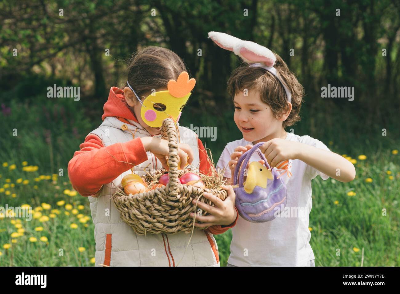 Two children hunt for Easter eggs in a spring garden. Easter tradition ...