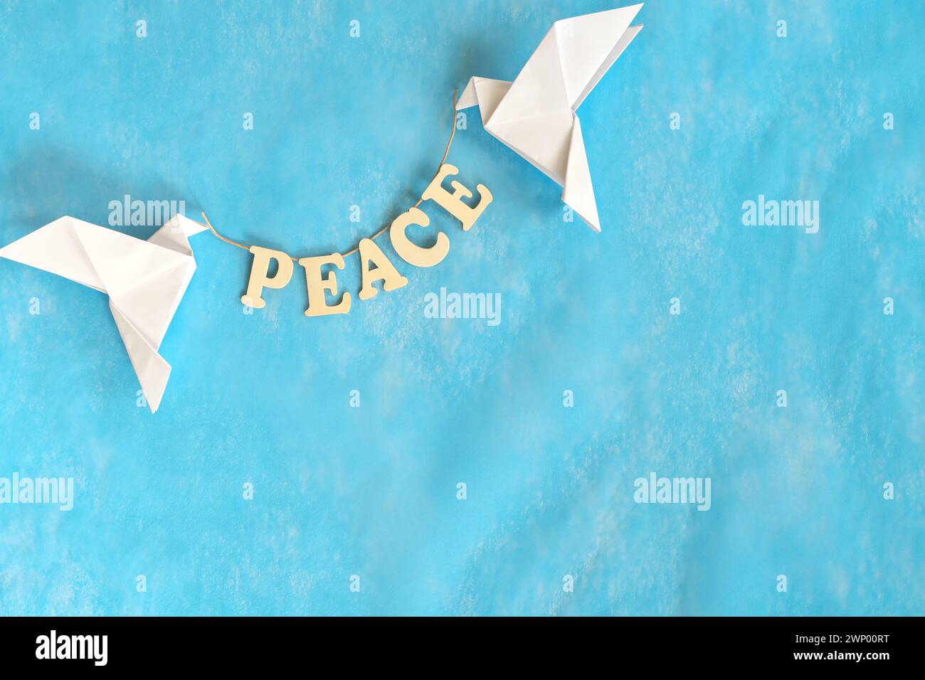 Message of peace. White dove origami carrying word letters in sky blue ...