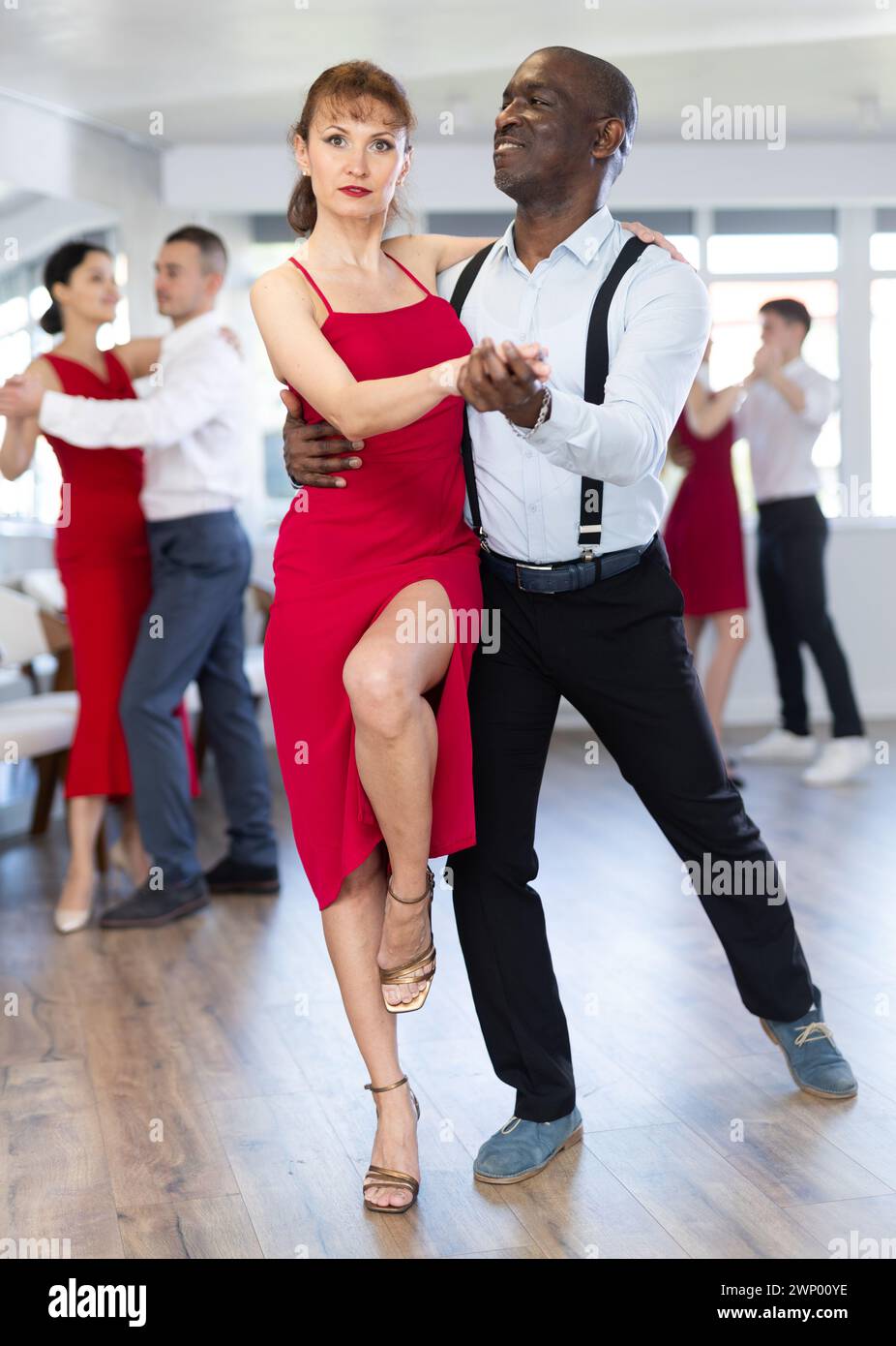 Woman in red and African American performing tango in dance class Stock ...