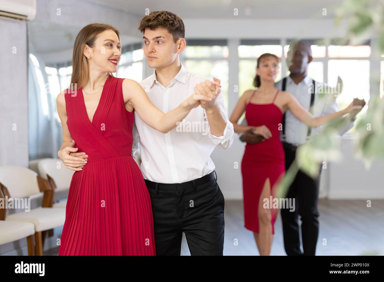 Young man and girl dancing tango in couple during lesson at studio ...
