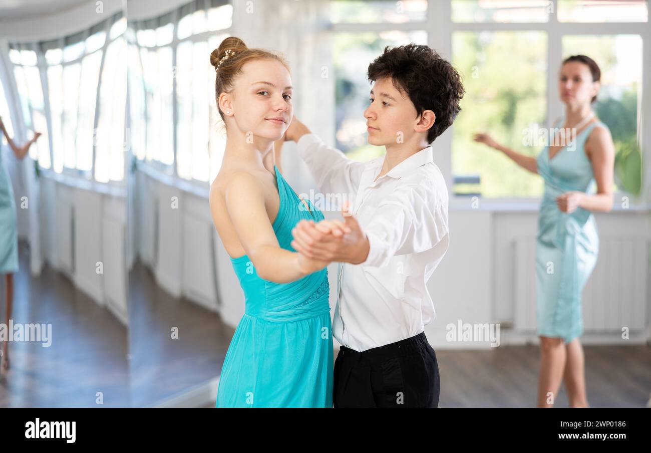 Girl and a boy in festive clothes learn to dance tango under guidance ...