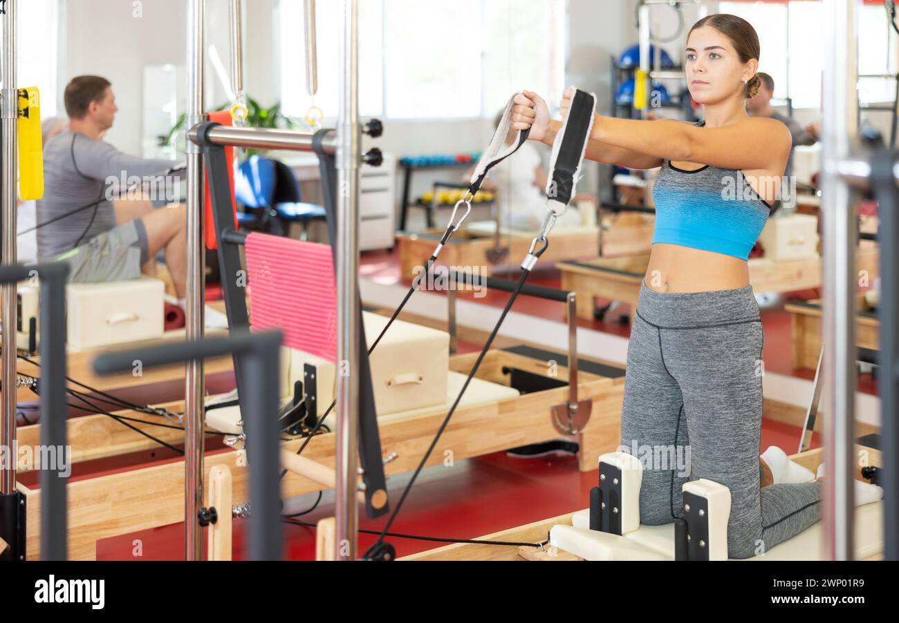 Sports club girl client on reformer with cable and rope performs ...