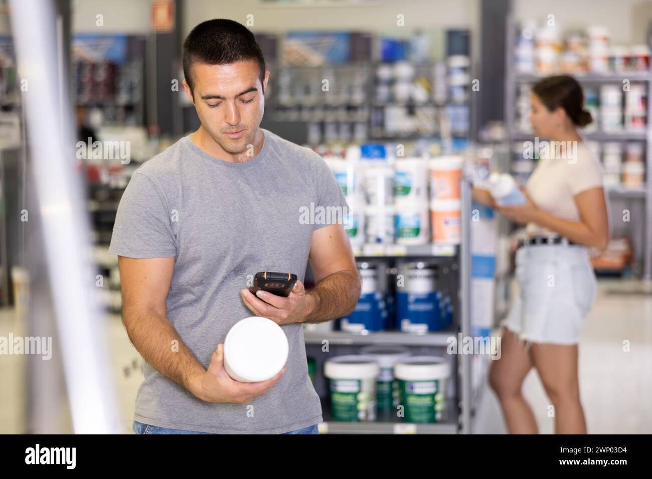 Male shopper scanning a QR code using a mobile phone in hardware store ...