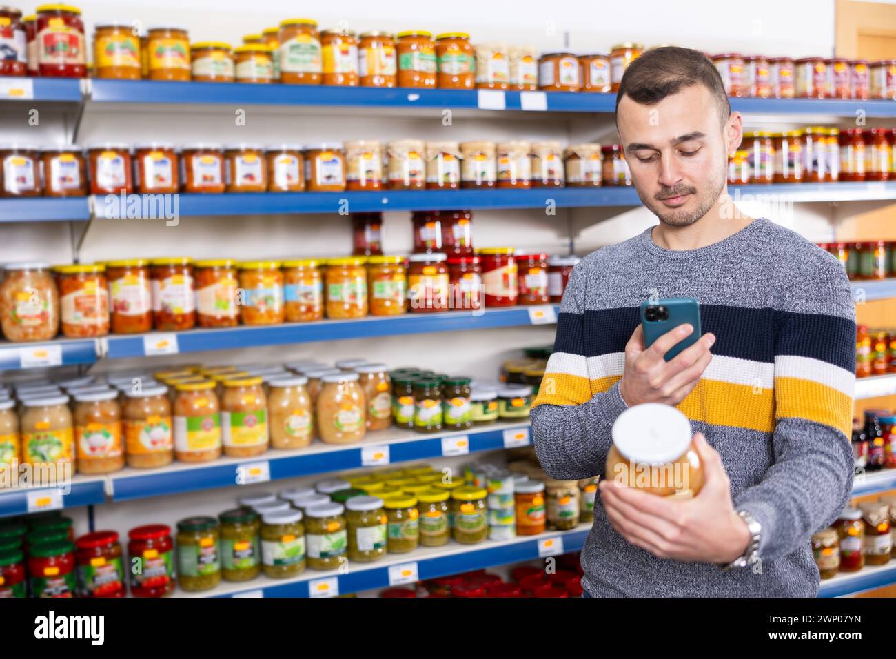 In Russian goods store, man choose jar of pickled fermented cabbage and ...