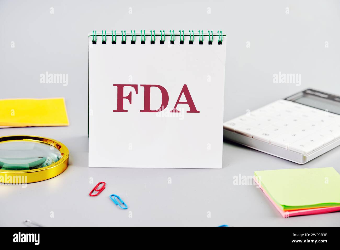 Word FDA written on a blank sheet of notepad next to office supplies on ...