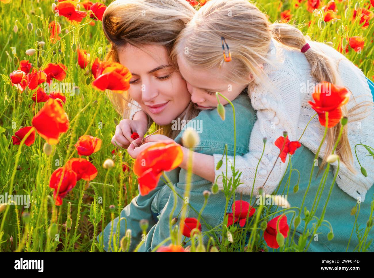 Mother and daughter hugging in a poppies meadow. Mom and child girl ...