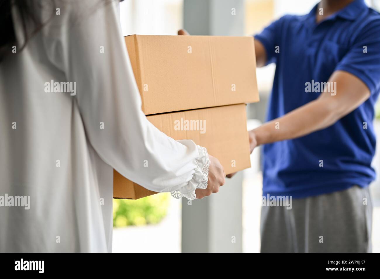A close-up image of a woman in pajamas receiving cardboard parcel boxes ...