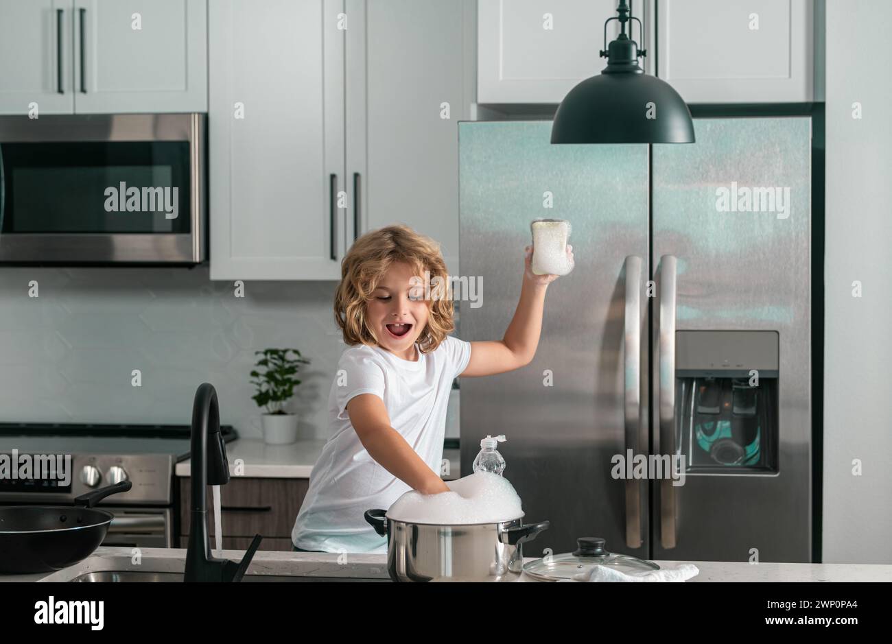 Funny twin boys helping in kitchen with washing dishes. Children having ...