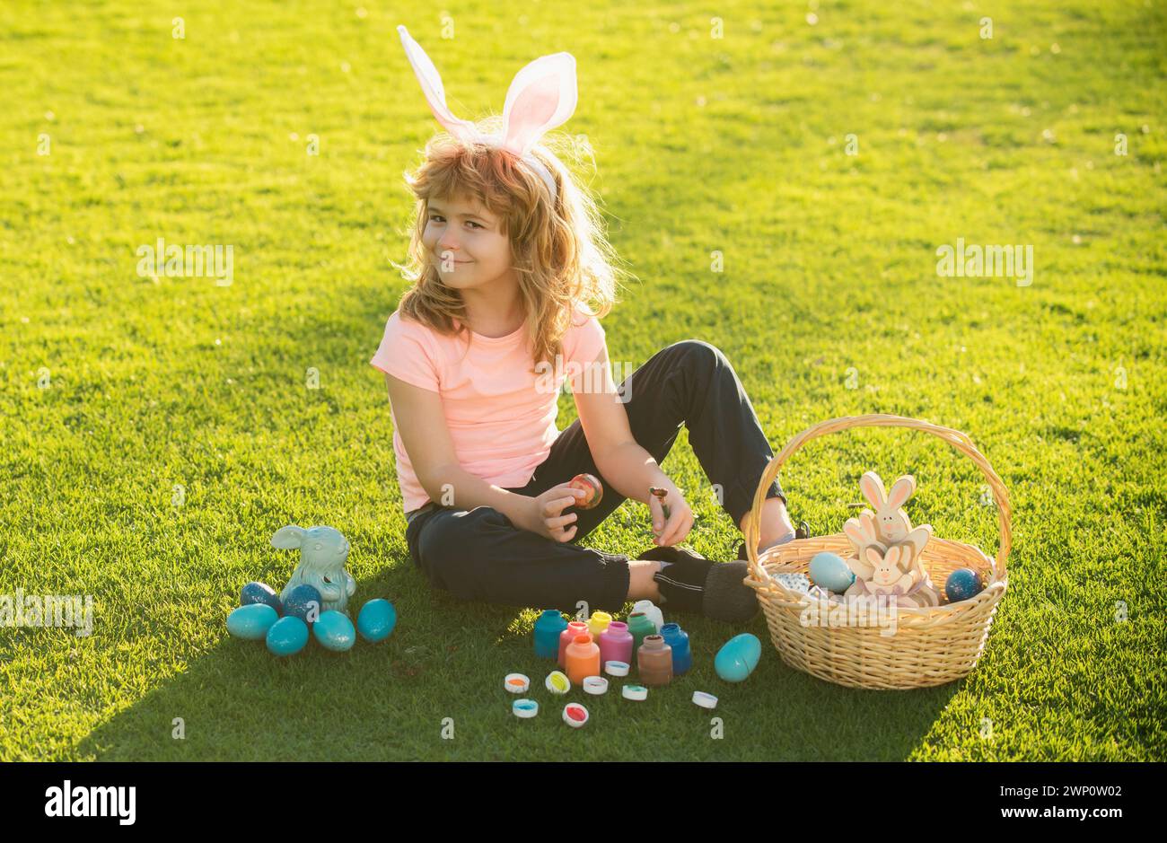 Easter bunny kids. Child boy in bunny Easter ears painting eggs. Cute ...