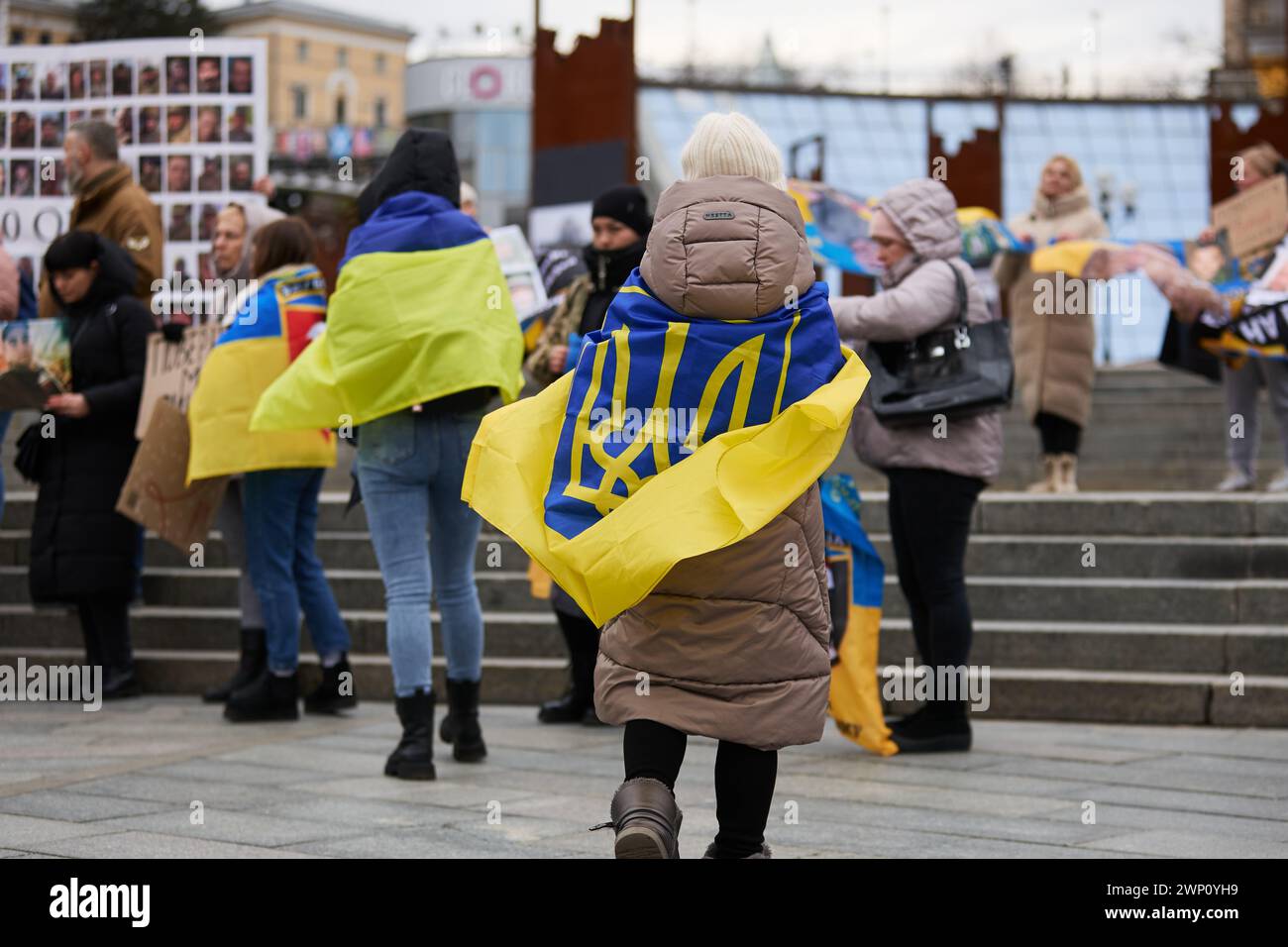 Patriotic young girl wearing a national flag of Ukraine on a public ...
