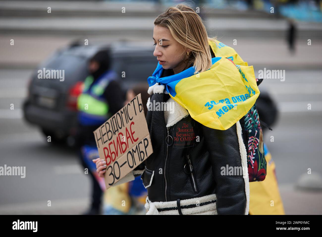 Sad Ukrainian woman wearing a national flag on shoulders and holding a ...